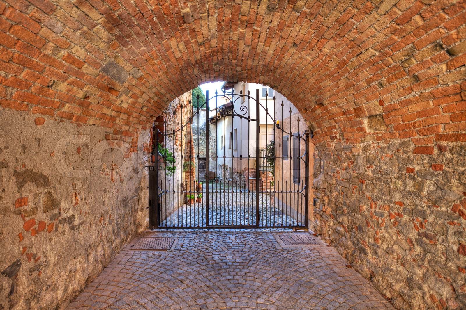 Old brick arched passage leading towards metal gate at the entrance to ...