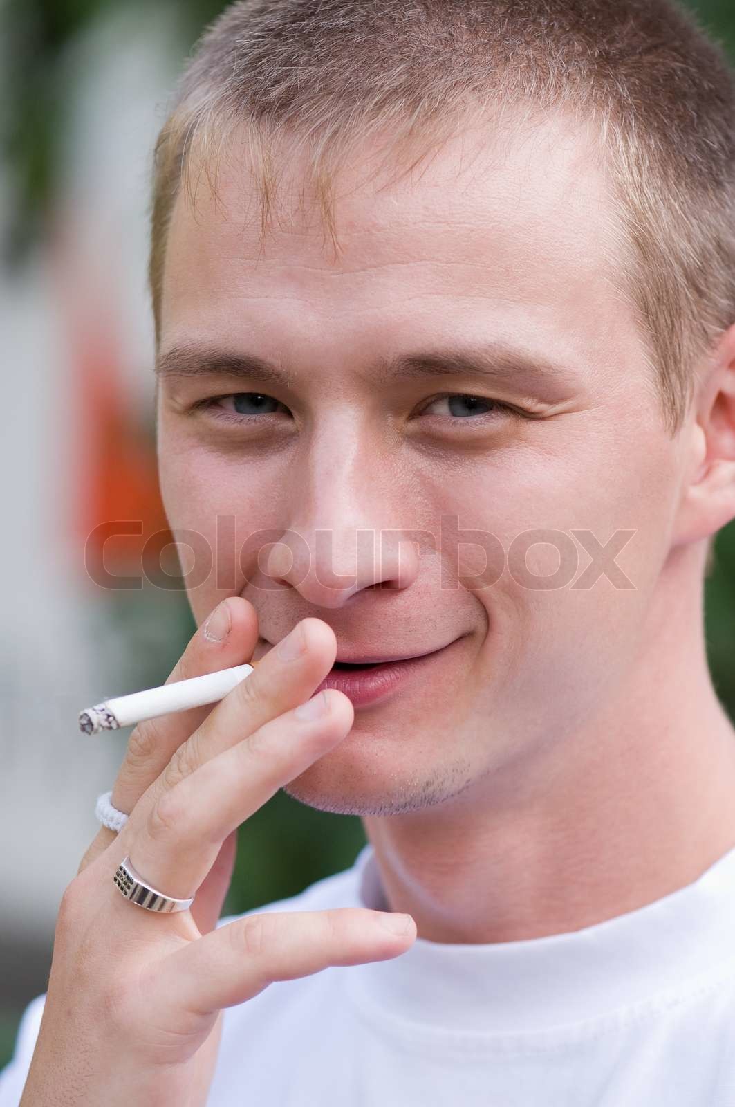 A young man smoking cigarette, focus is set at his face | Stock image ...
