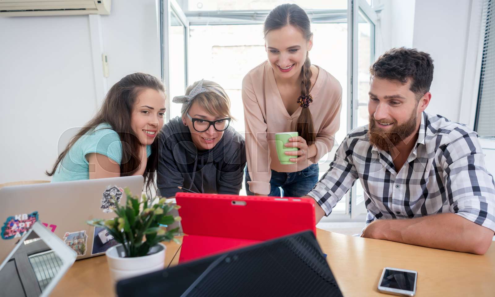 Four co-workers watching a business presentation in a modern shared ...