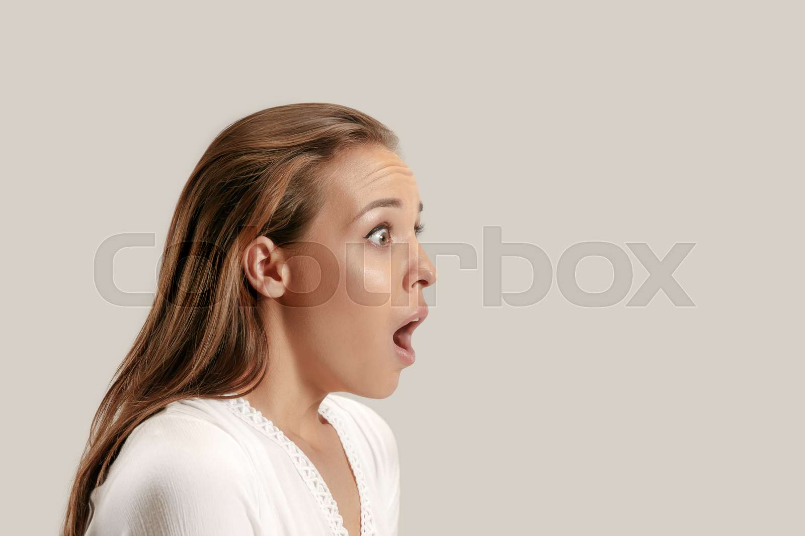 Beautiful woman looking suprised isolated on gray | Stock image | Colourbox