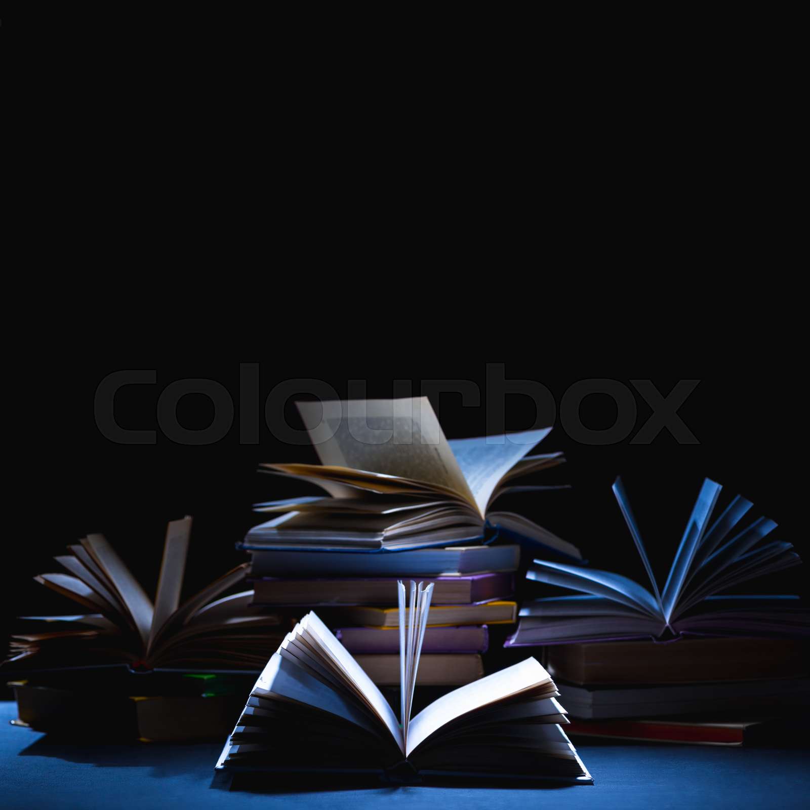 stack of different books on dark tabletop on black | Stock image ...