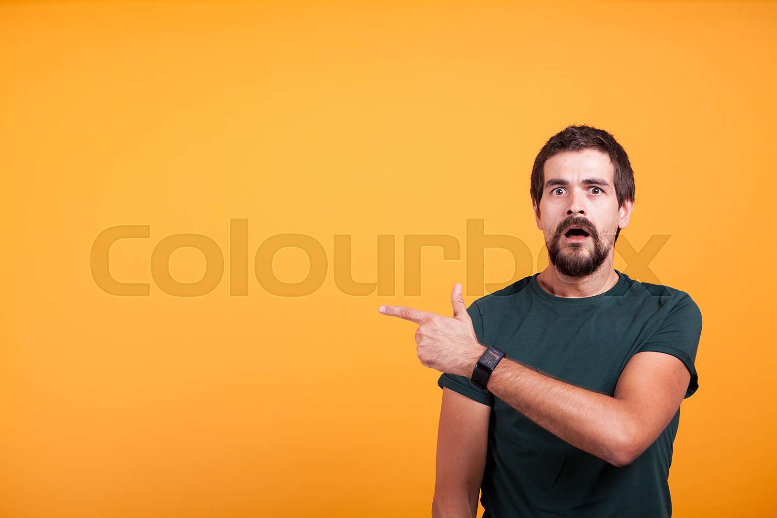 Expressive shocked man pointing at his right with his mouth open ...