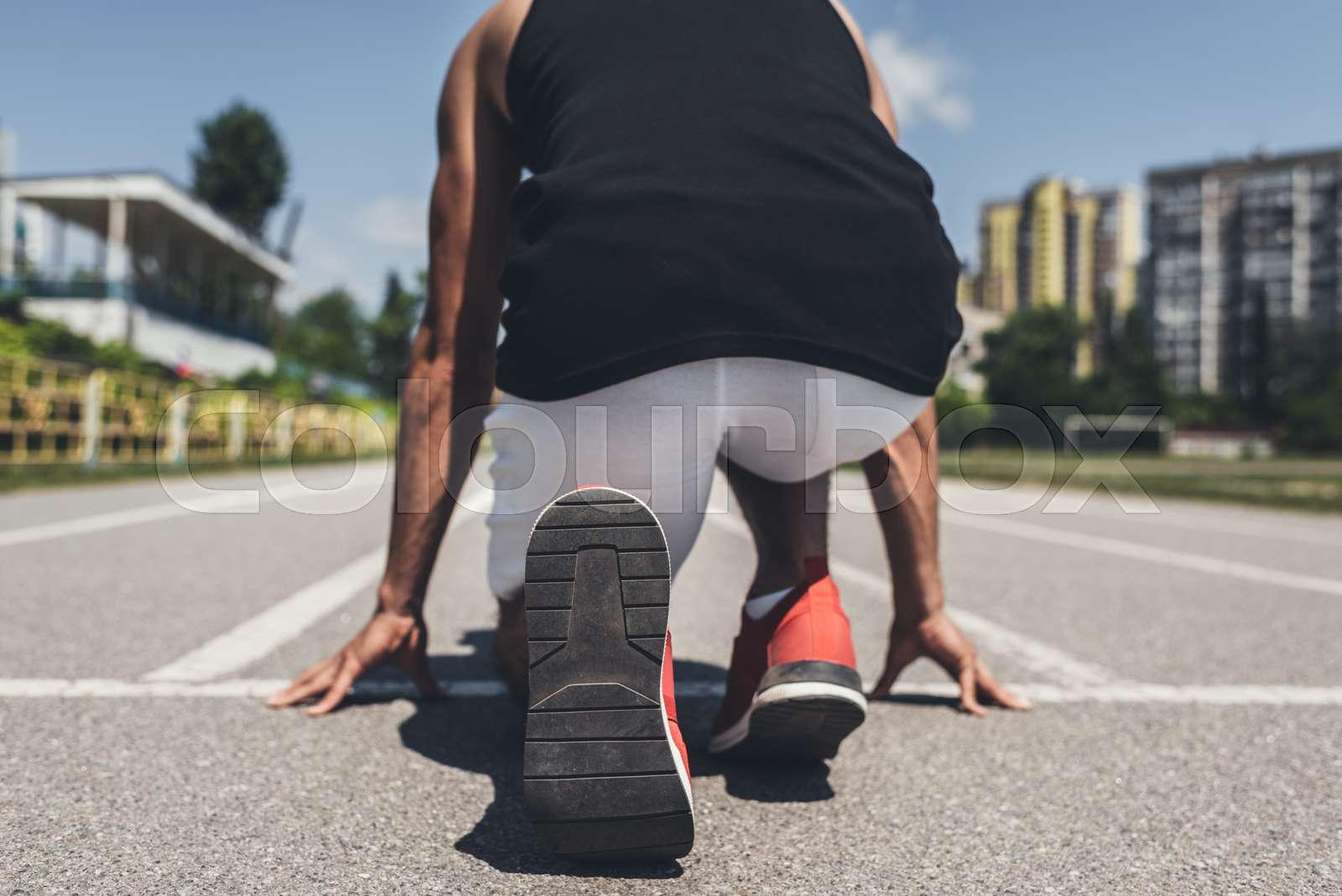back view of male athlete in starting position on running track | Stock ...
