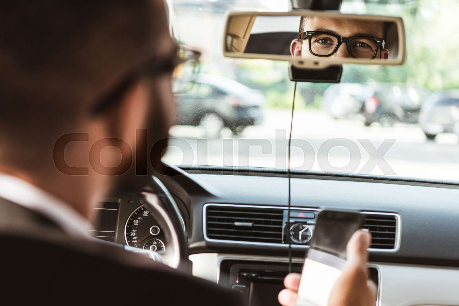 handsome driver looking at mirror in car | Stock image | Colourbox