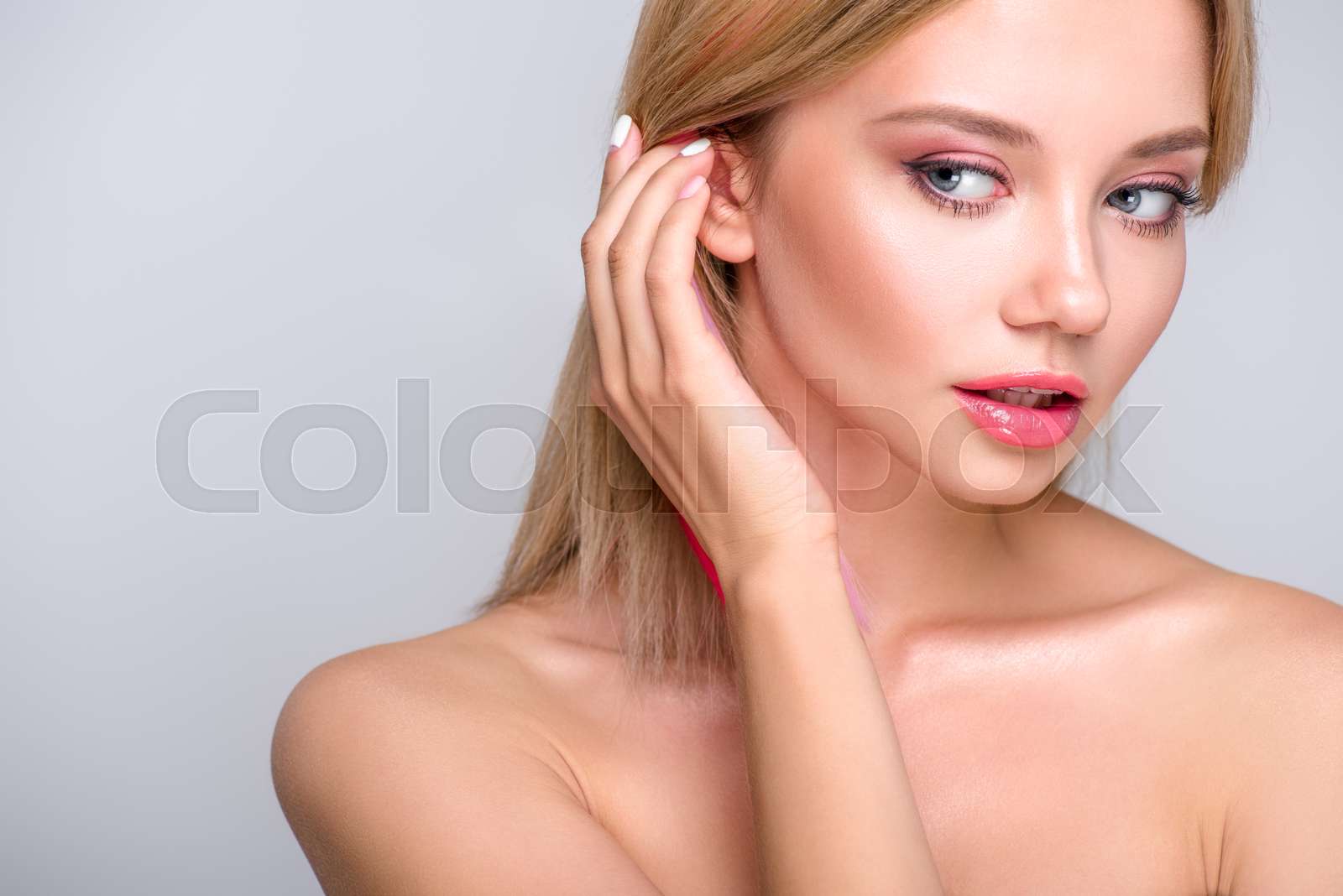 close-up portrait of beautiful young woman putting hair behind ear ...