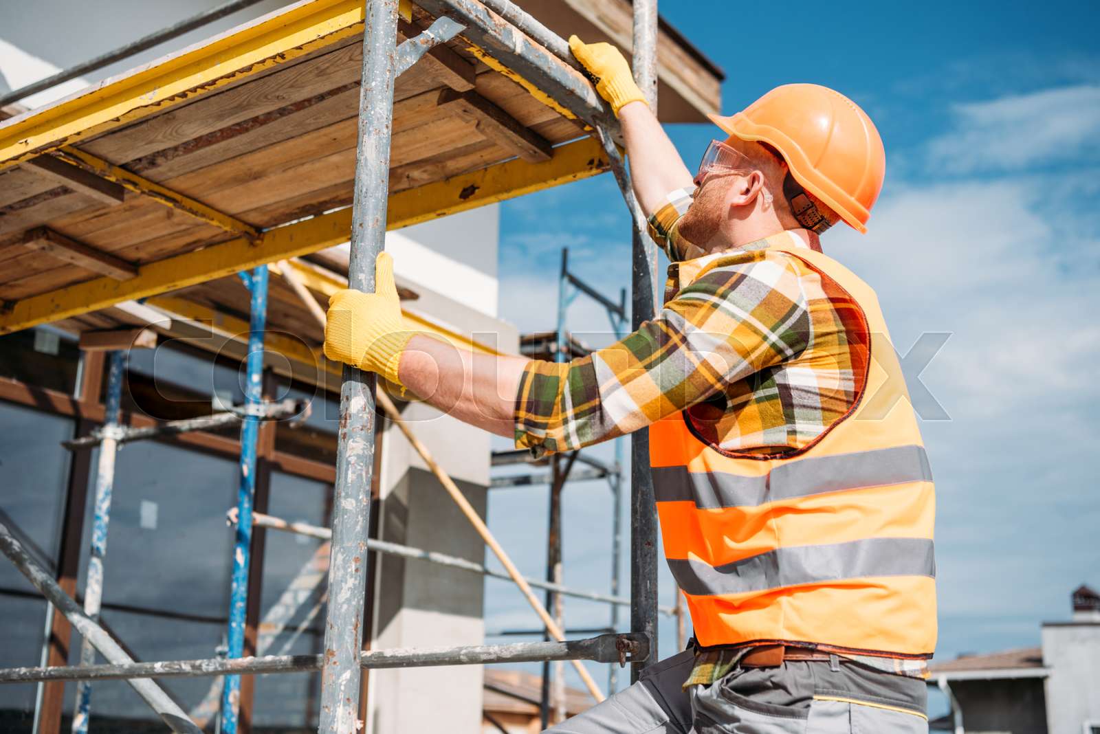 handsome builder climbing on scaffolding at construction site | Stock ...