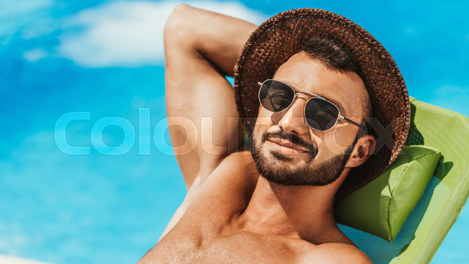 handsome man in sunglasses and straw hat sunbathing on sunbed at ...