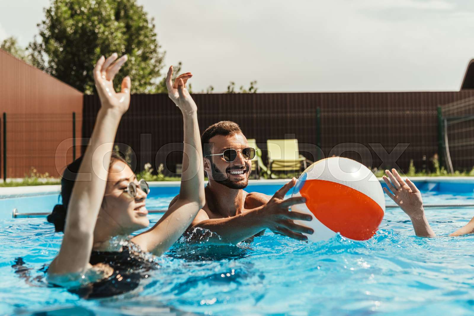 multiethnic friends playing with beach ball in swimming pool | Stock ...