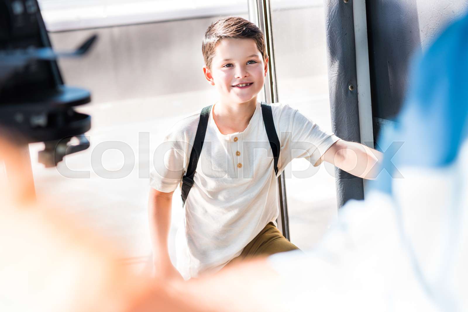 smiling schoolboy entering school bus and looking at driver | Stock ...