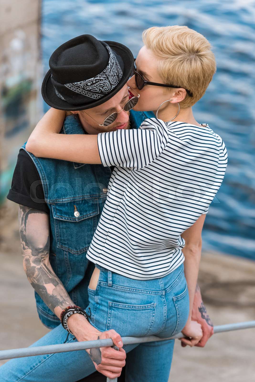 boyfriend with tattoos and stylish girlfriend hugging and leaning on ...