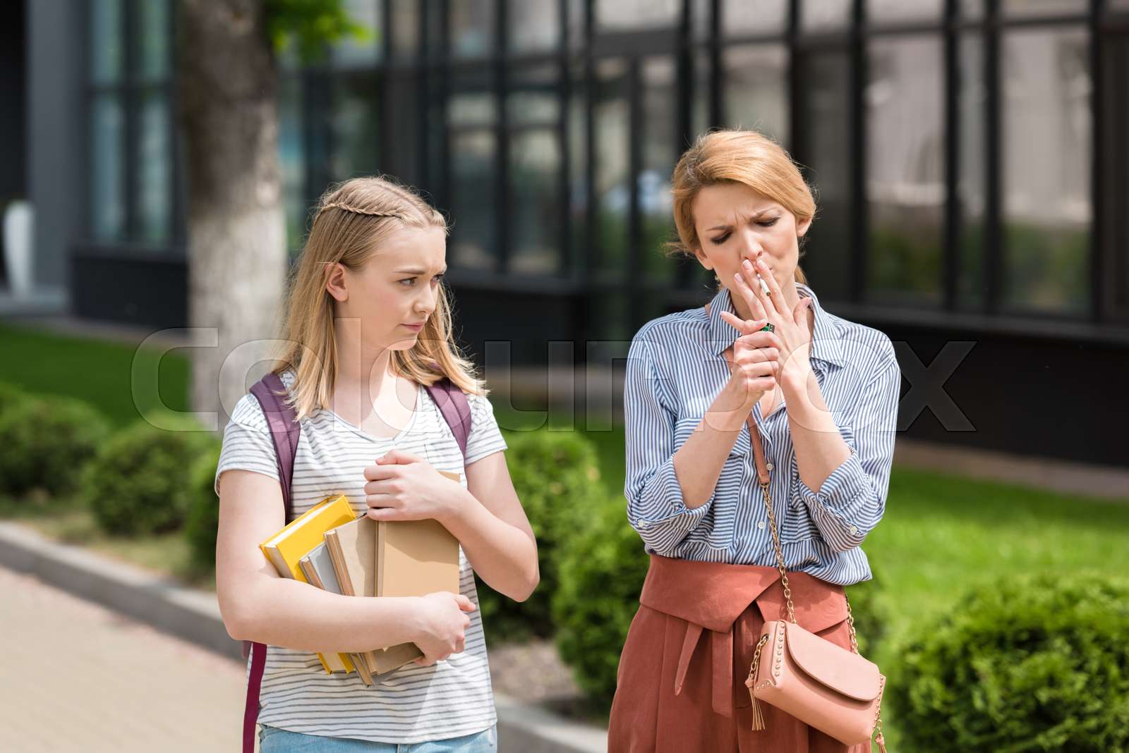disgusted teen daughter looking at mother while smoking cigarette ...