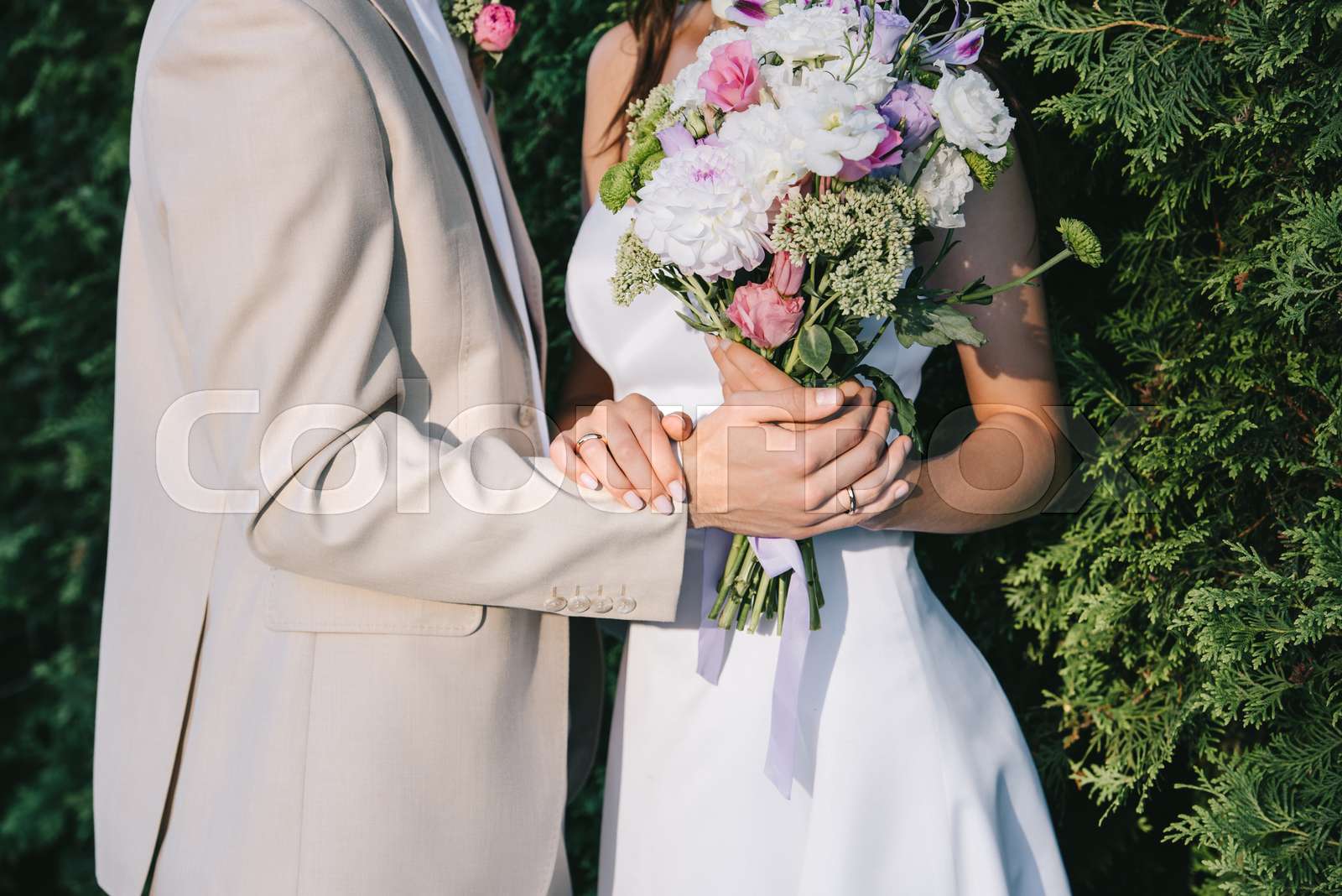 partial view of elegant wedding couple holding flower bouquet | Stock ...