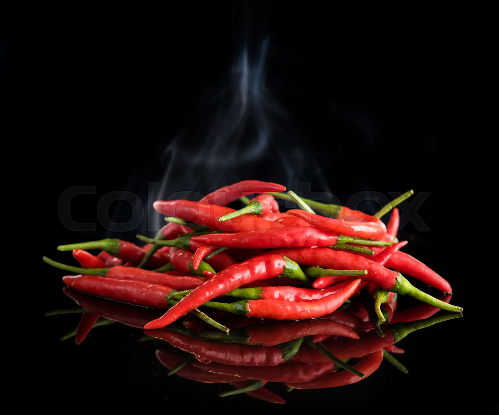 Hot chilli with smoke on black surface | Stock image | Colourbox