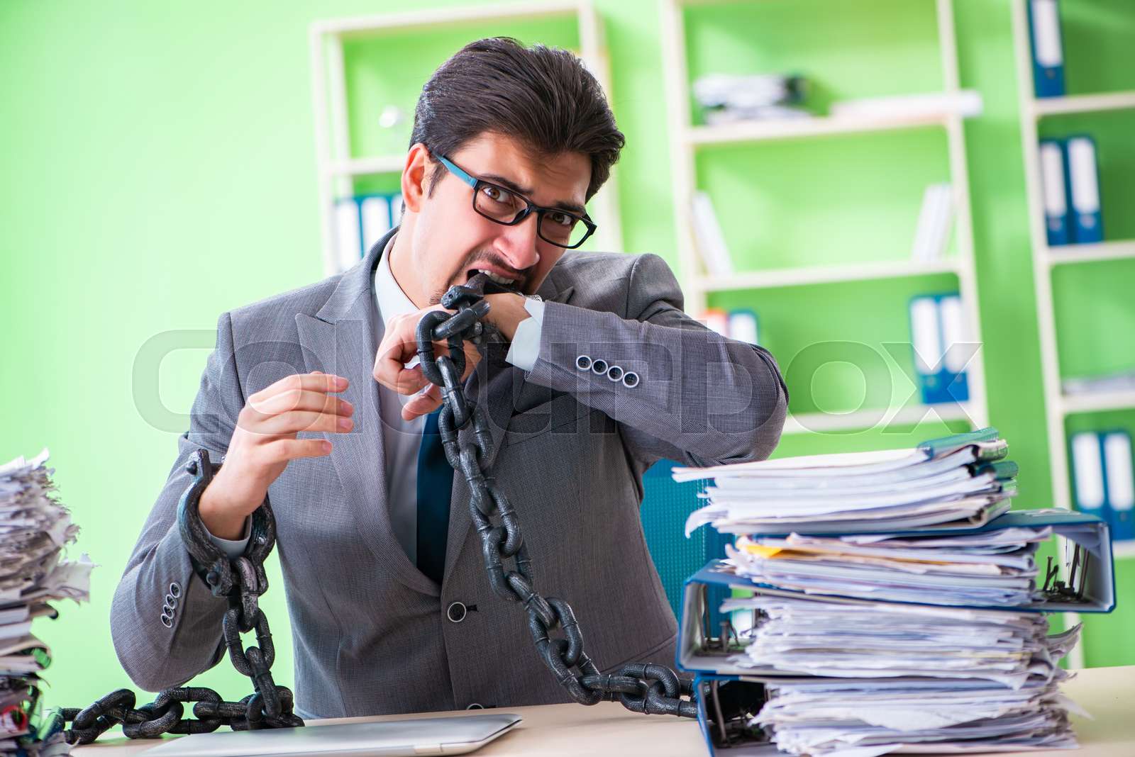 Employee chained to his desk due to workload | Stock image | Colourbox