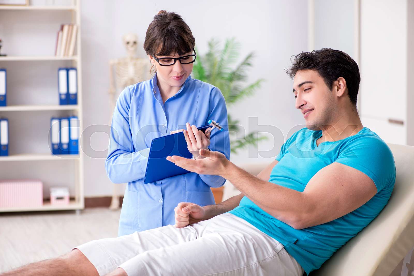 Doctor checking nerve reflexes with hammer | Stock image | Colourbox