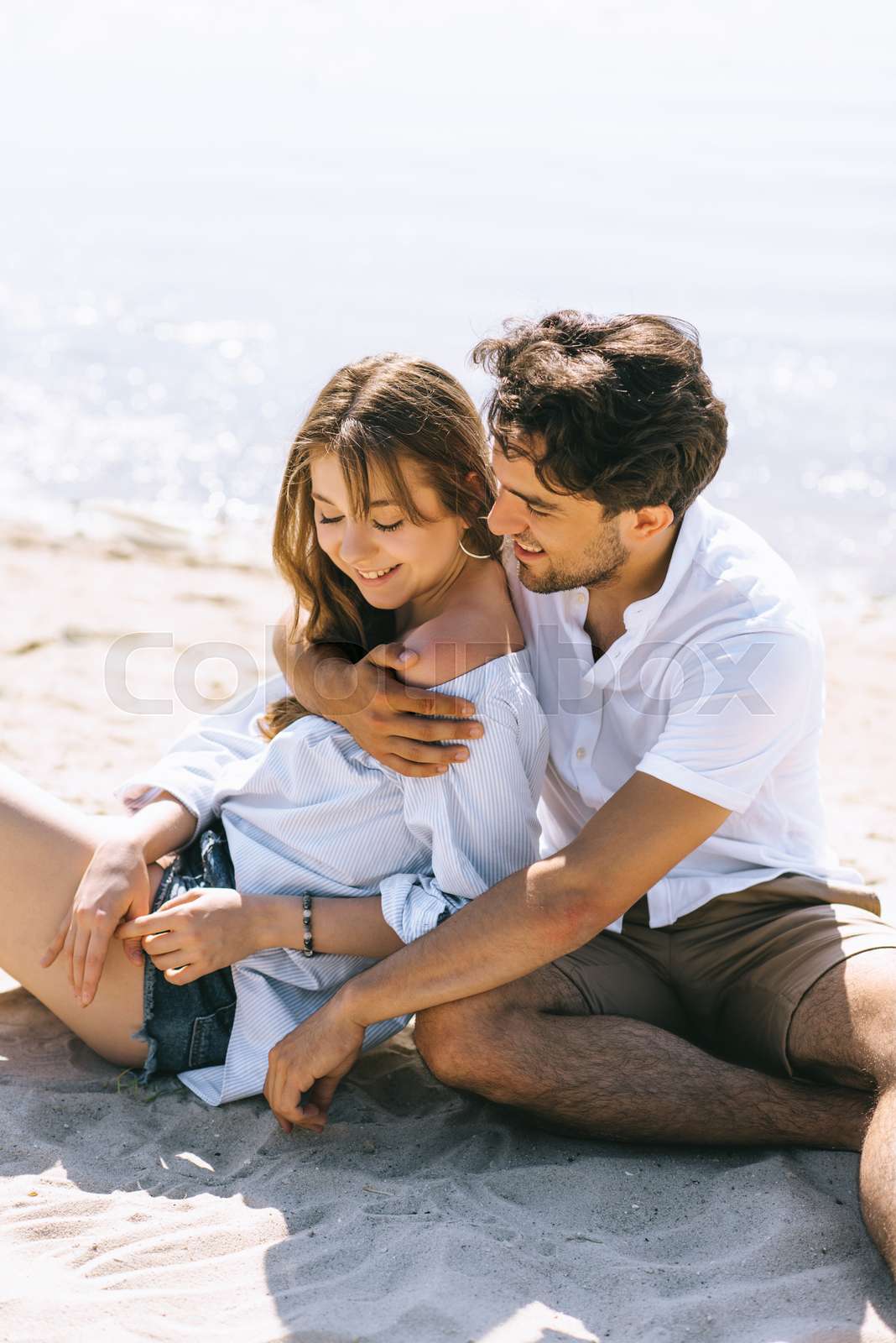 couple sitting and cuddling on sandy city beach near river | Stock ...