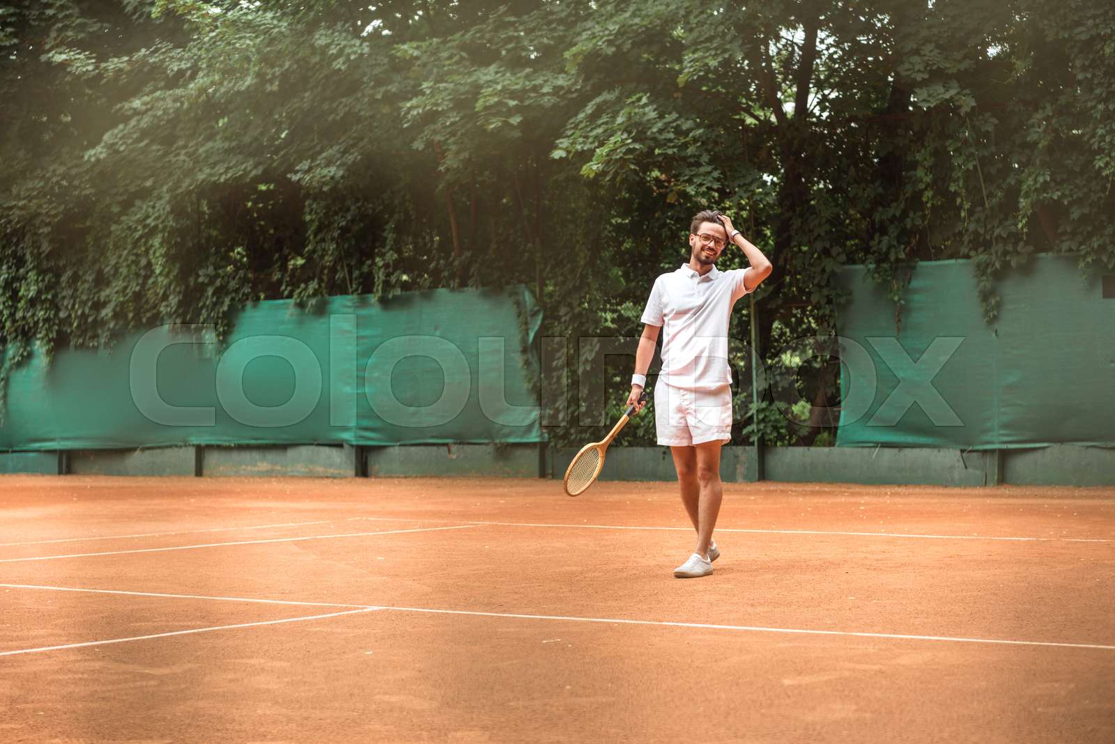 handsome tennis player with racket standing on tennis court | Stock ...