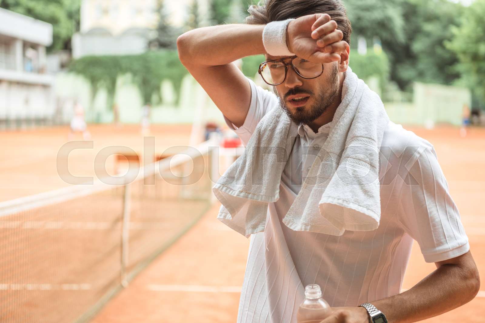 sweaty tired tennis player with towel after training on tennis court ...