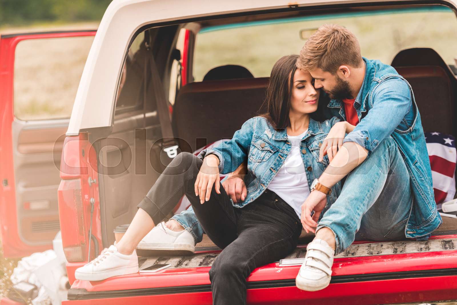 beautiful young couple cuddling in car trunk during trip | Stock image ...
