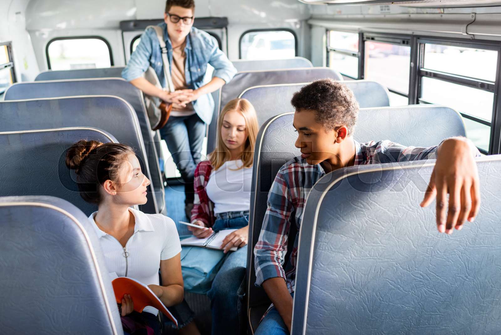 group of teen scholars riding school bus and spending time together ...