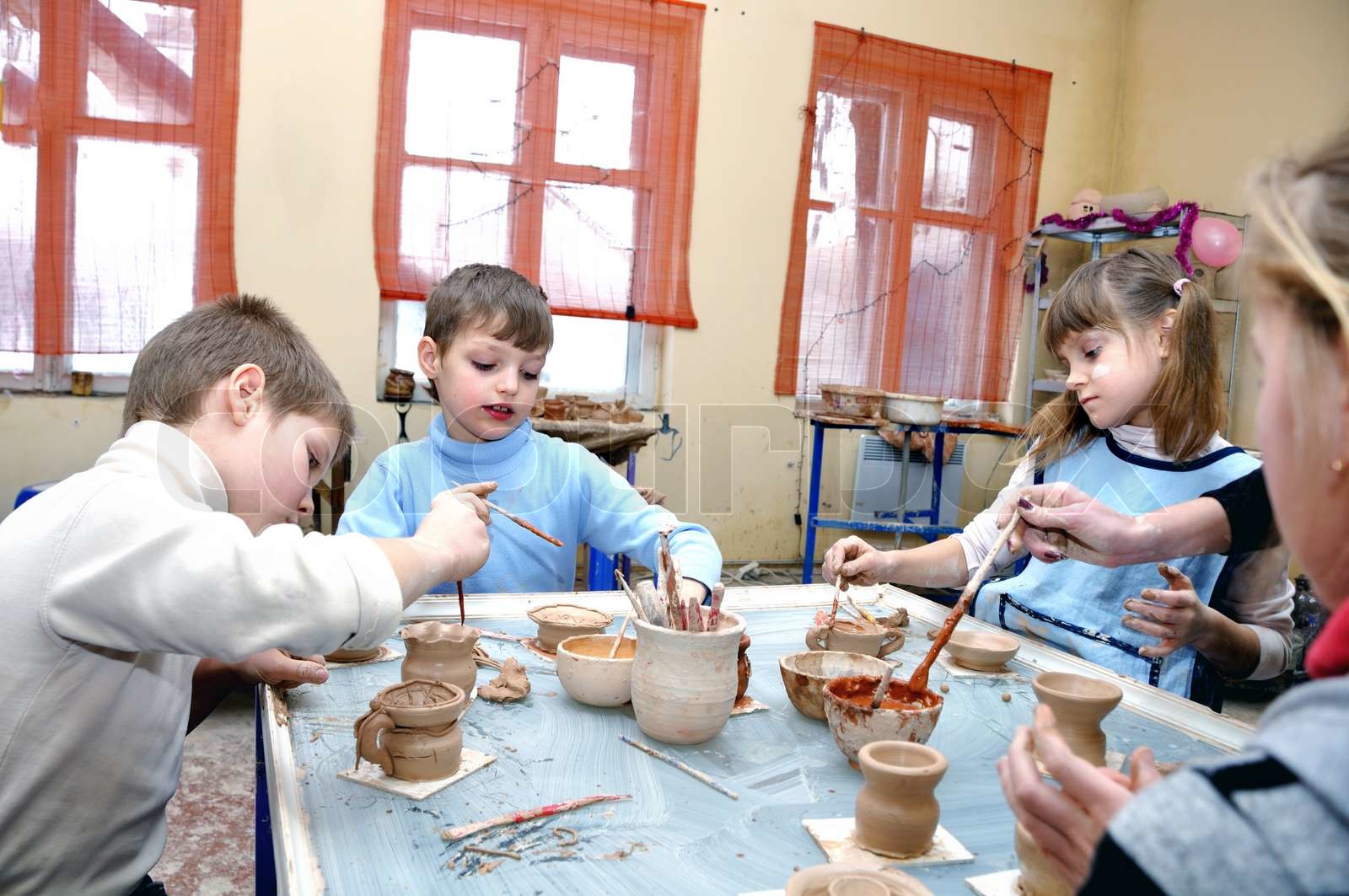 group of children shaping clay pots and vases in pottery studio school ...
