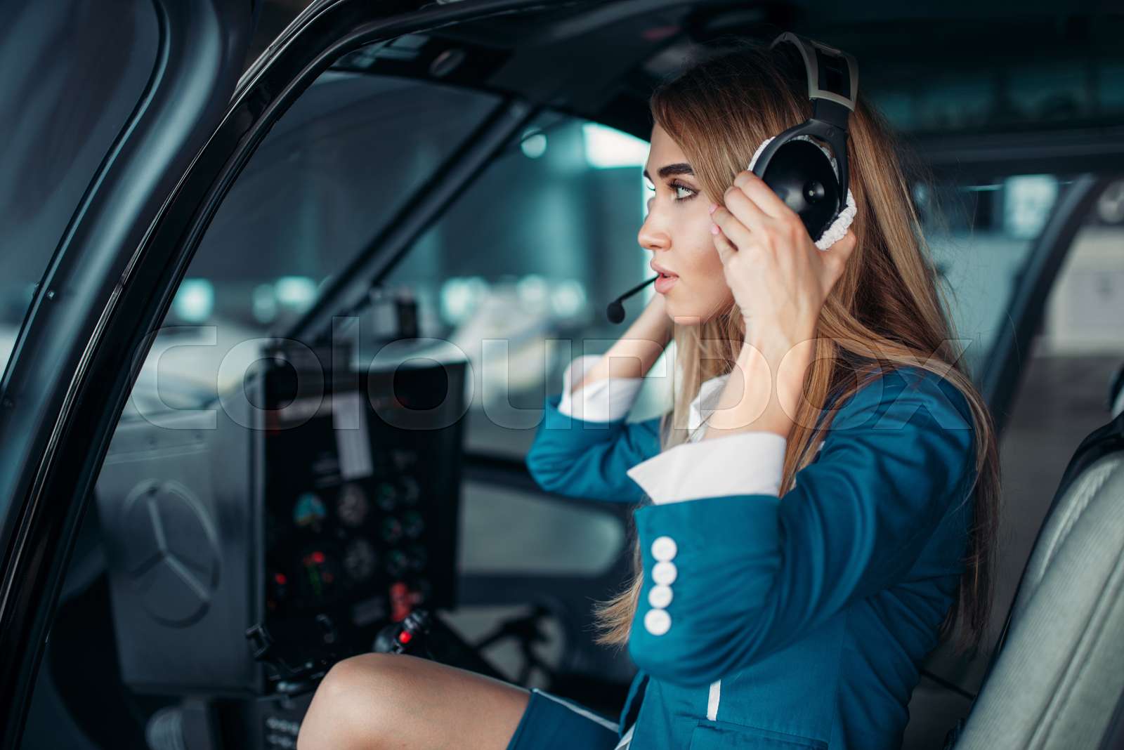 Female pilot in headphones in helicopter cabin | Stock image | Colourbox