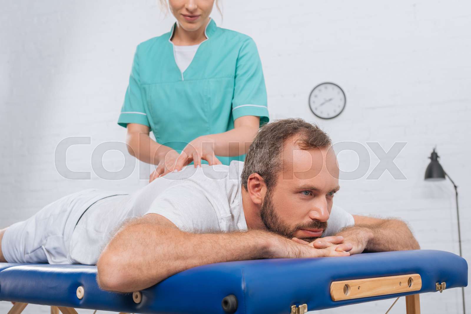 partial view of female massage therapist doing massage to patient on ...