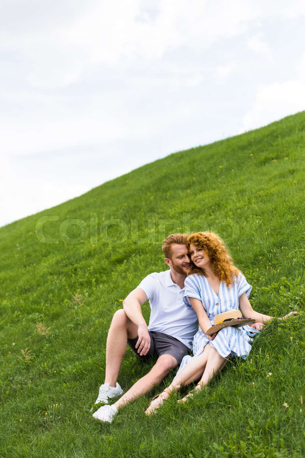 happy redhead couple sitting on grassy hill | Stock image | Colourbox