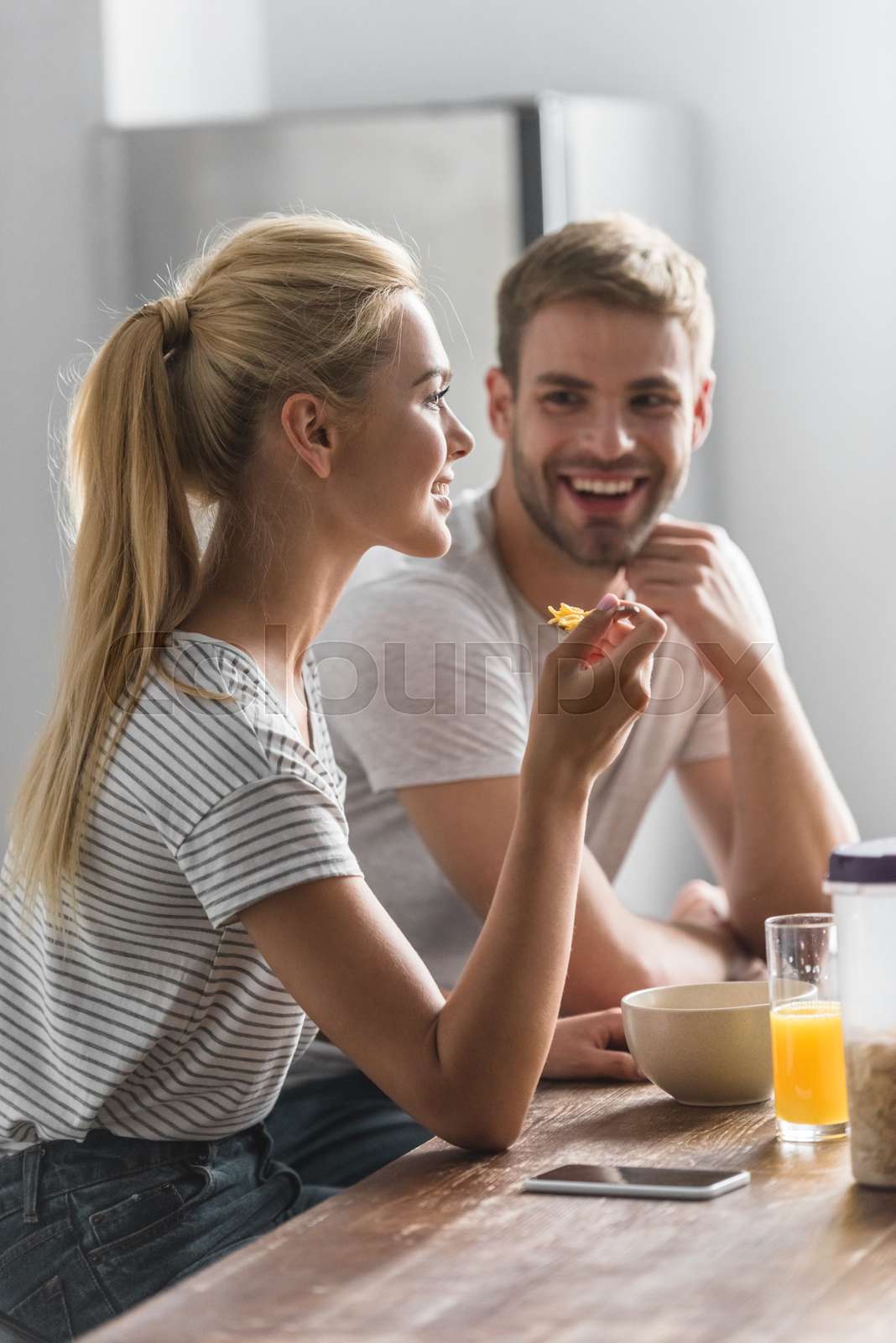 happy boyfriend looking at girlfriend during breakfast in kitchen ...