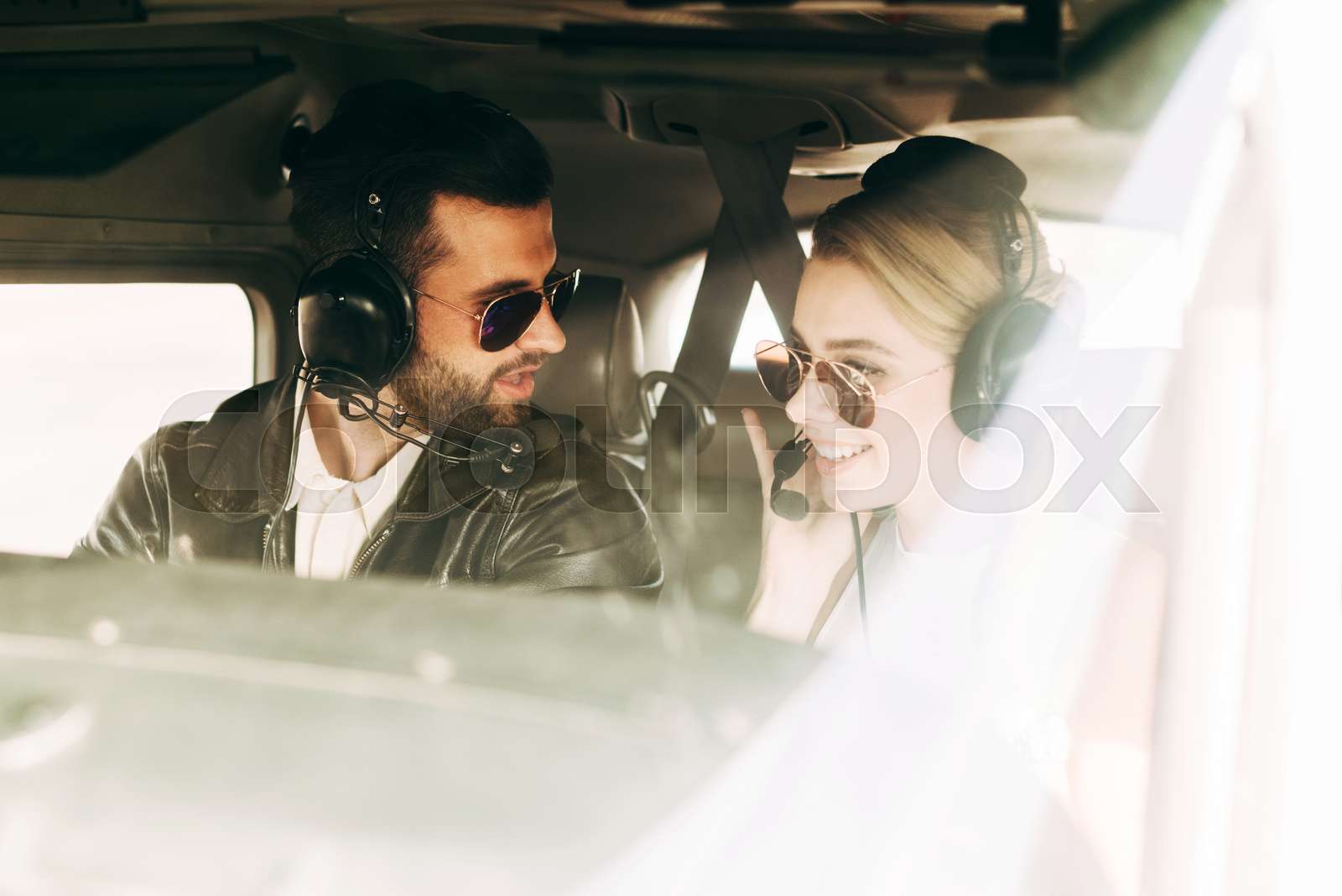 male pilot in headset and sunglasses talking to girlfriend in cabin of ...