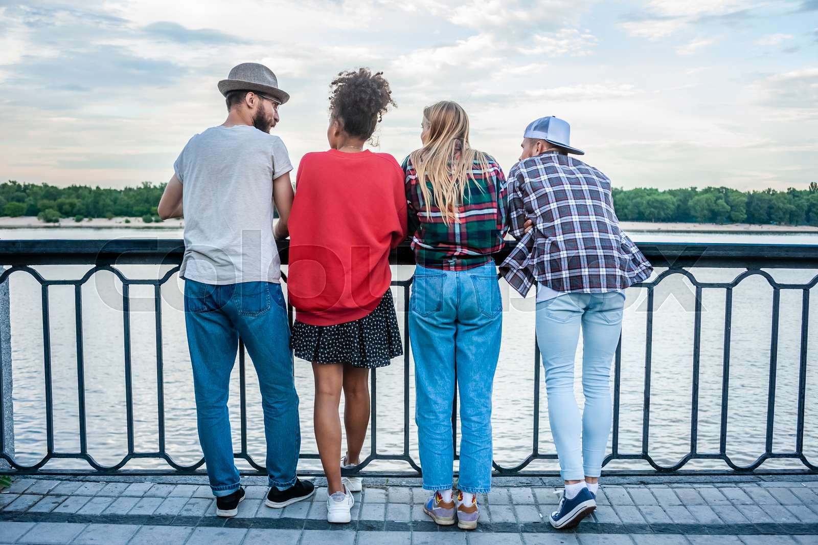 back view of four young multiethnic friends standing together on ...