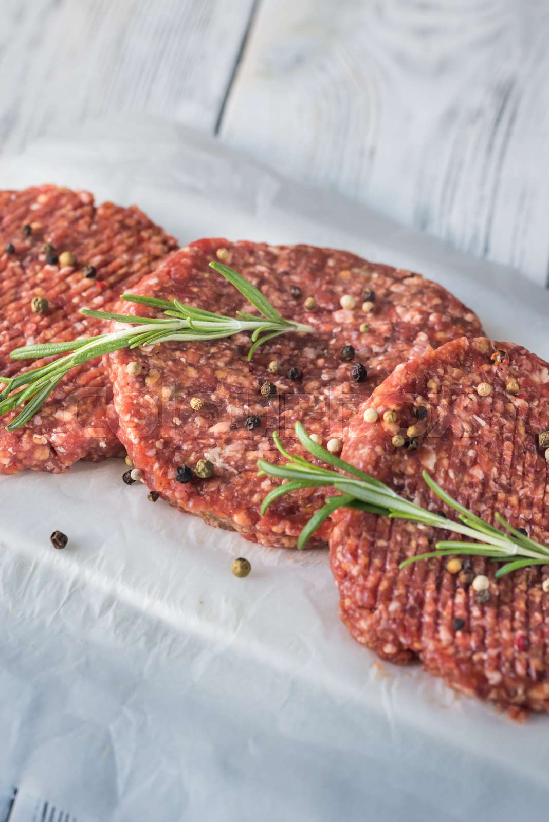 Raw beef patties on the white parchment | Stock image | Colourbox