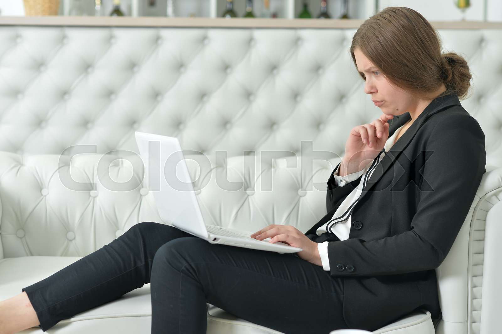 Portrait of thoughtful teen girl wearing formal wear using lapto ...