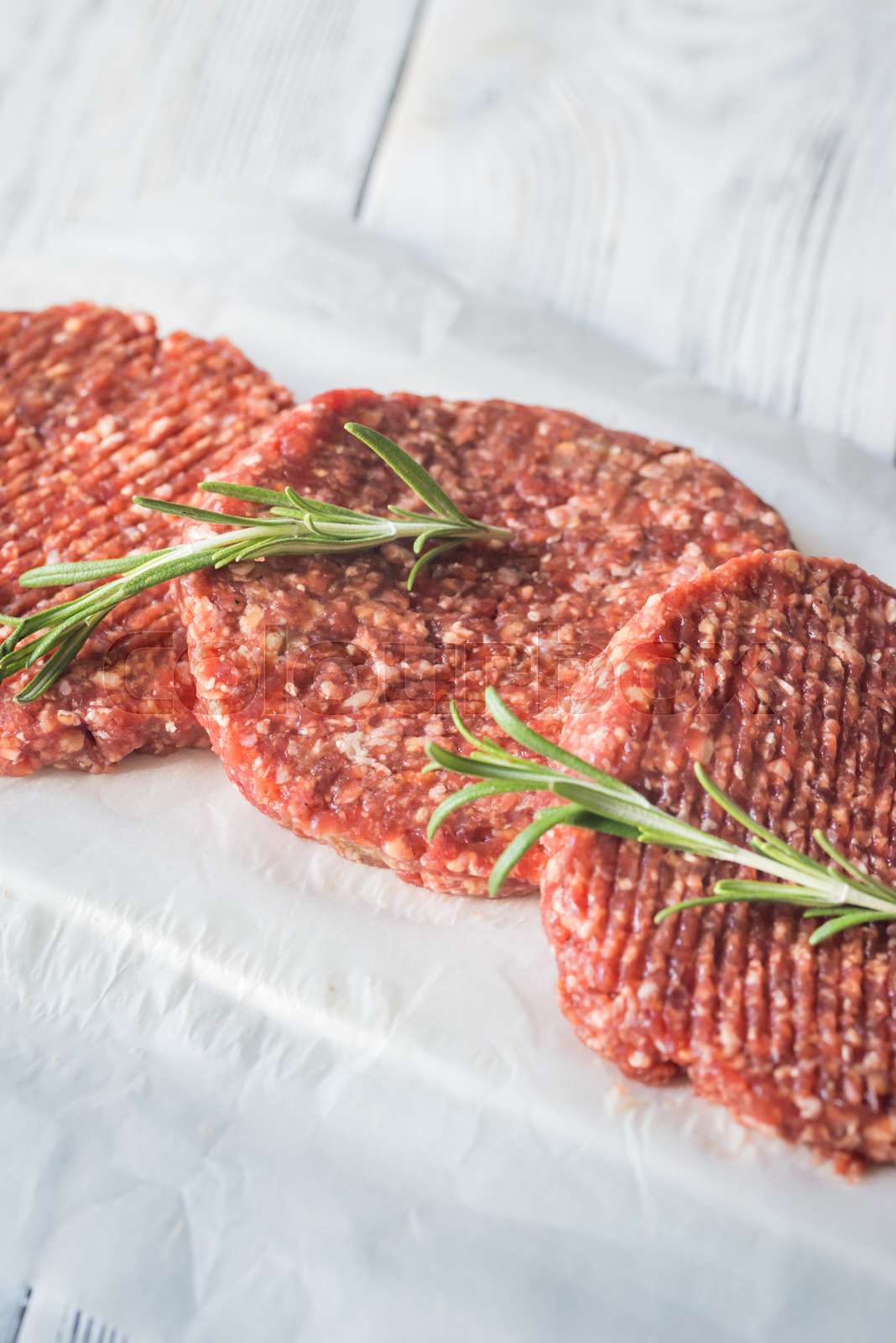 Raw beef patties on the white parchment | Stock image | Colourbox