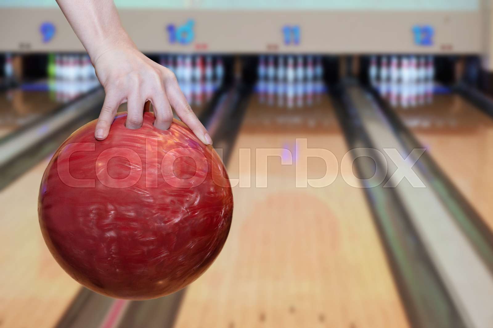 Close-up on woman hand holding bowling ball against bowling alley ...