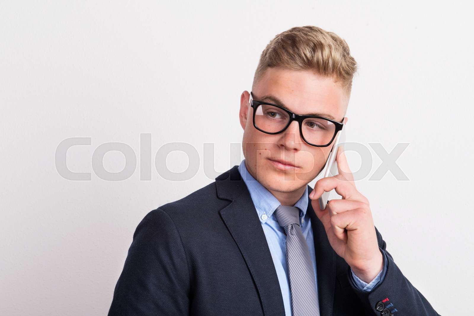 Portrait of a young man with smartphone in a studio, making a phone ...