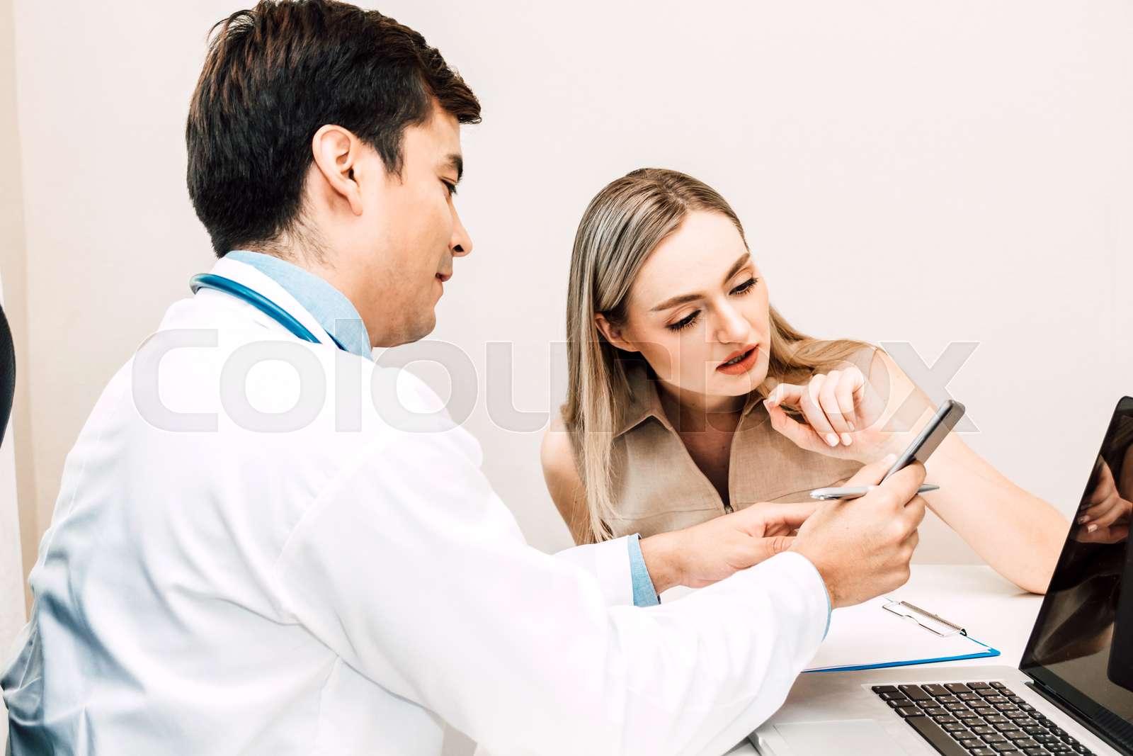 Doctor discussing and consulting with female patien on doctors table in ...