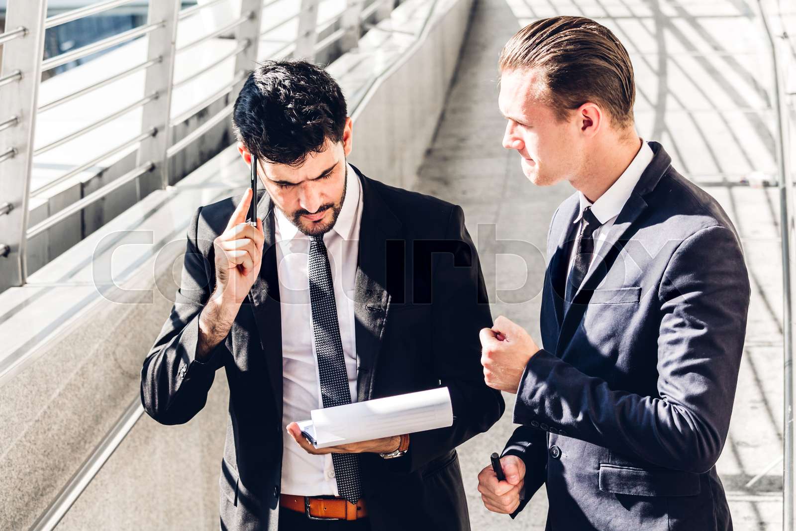 Two smiling businessman coworkers in black suit talking and working ...