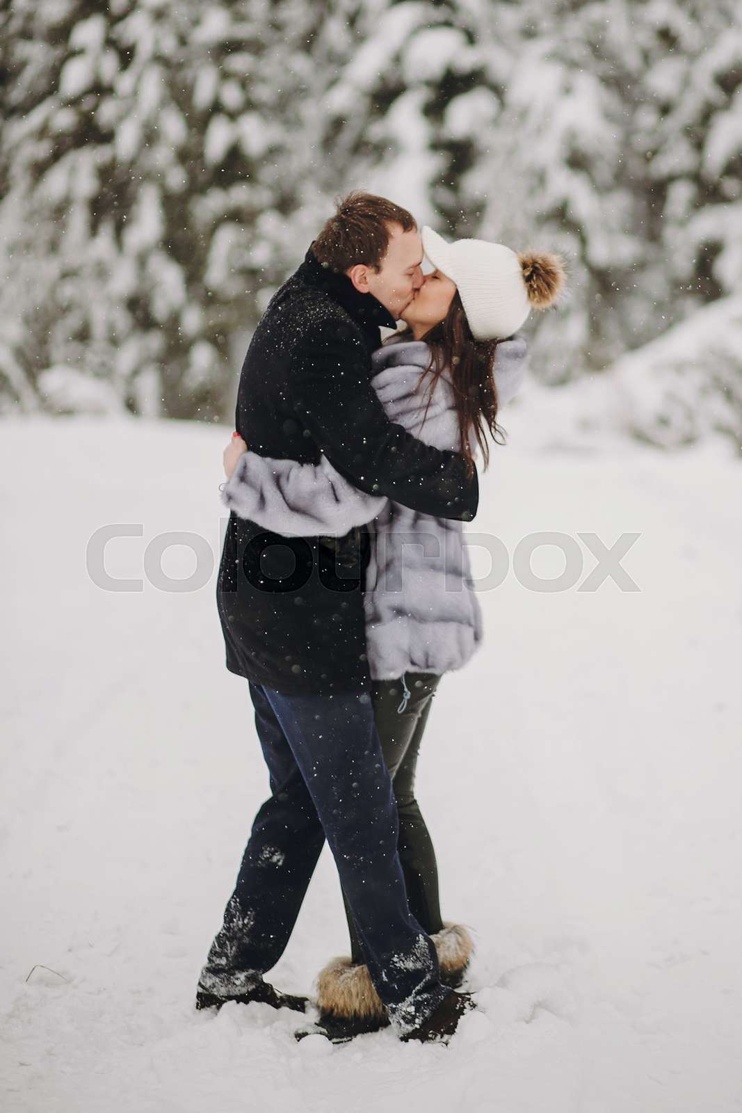 Stylish couple in love gently kissing in snowy mountains. Portraits of happy family gently ...