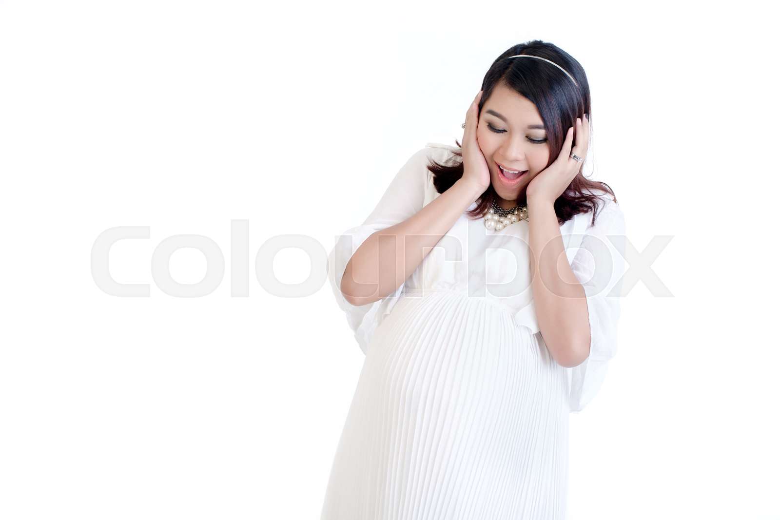 Excited pregnant woman looking at her belly | Stock image | Colourbox