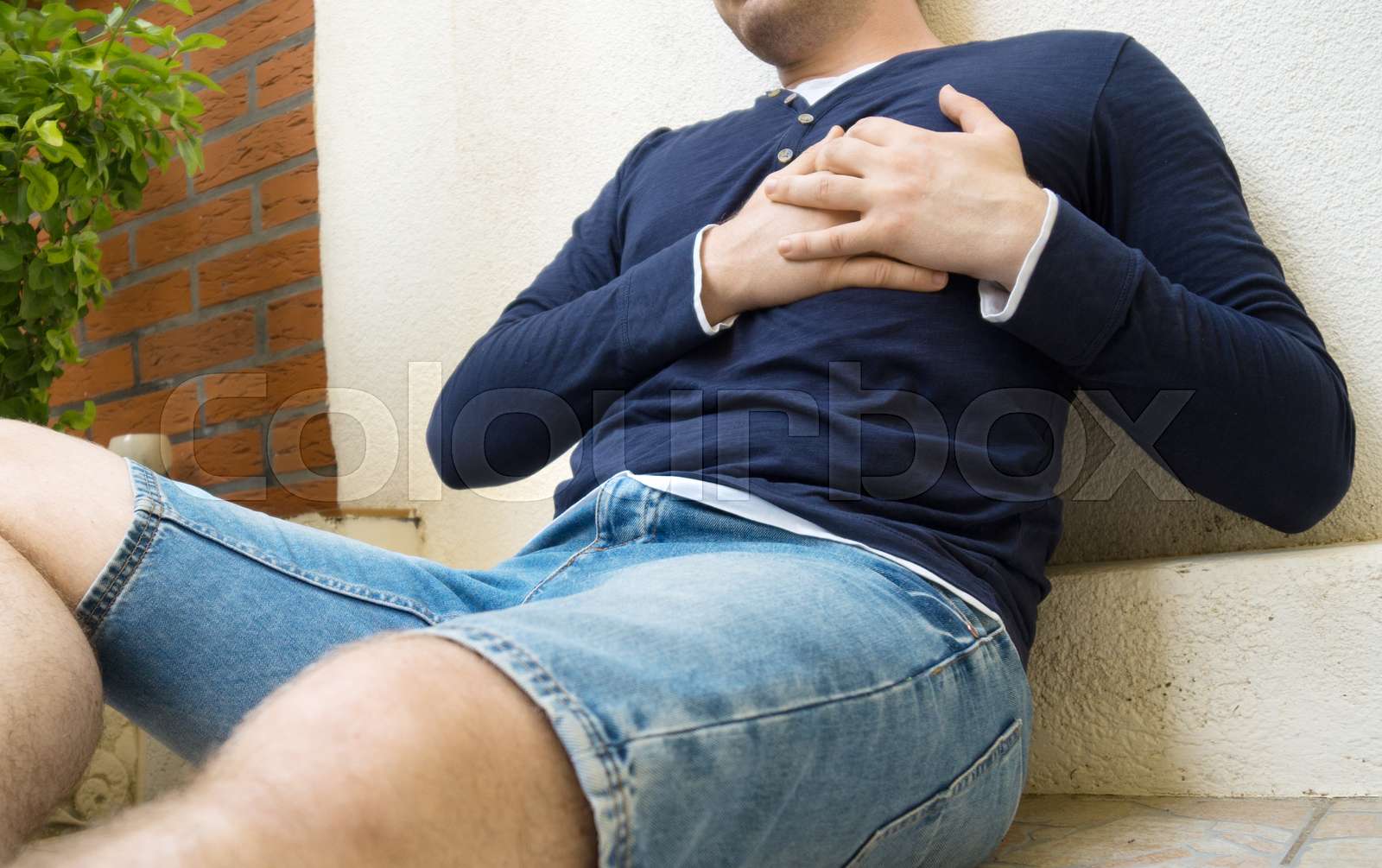 Man with a heart attack sitting on the ground. | Stock image | Colourbox