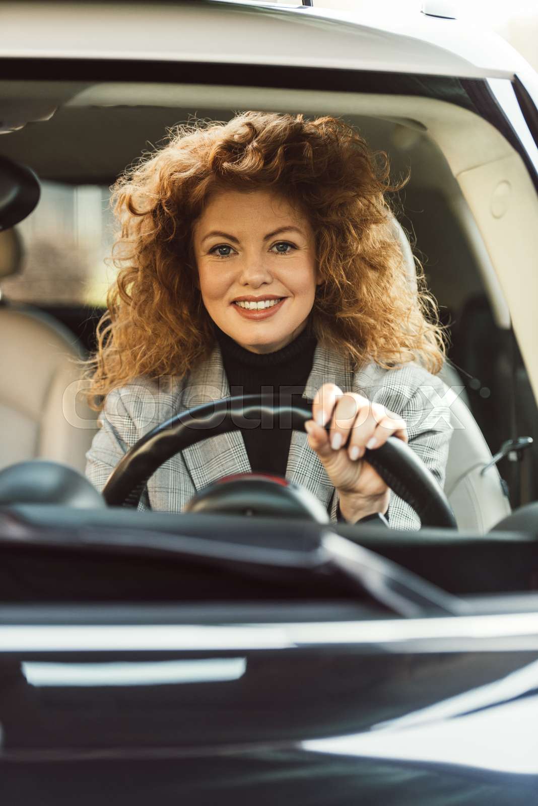 smiling attractive curly redhead woman driving car | Stock image ...