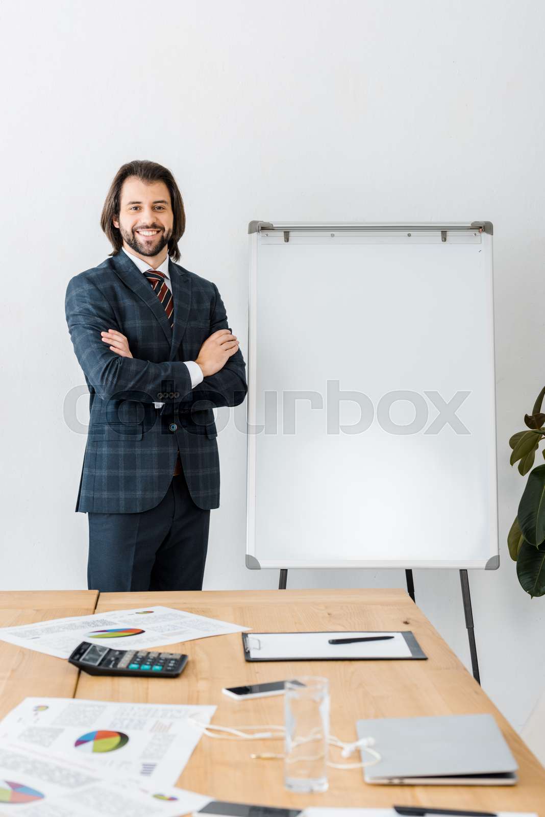 young smiling male insurance agent standing with arms crossed near ...