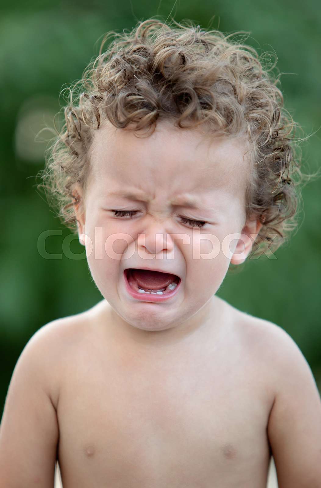 Sad baby with curly hair crying | Stock image | Colourbox