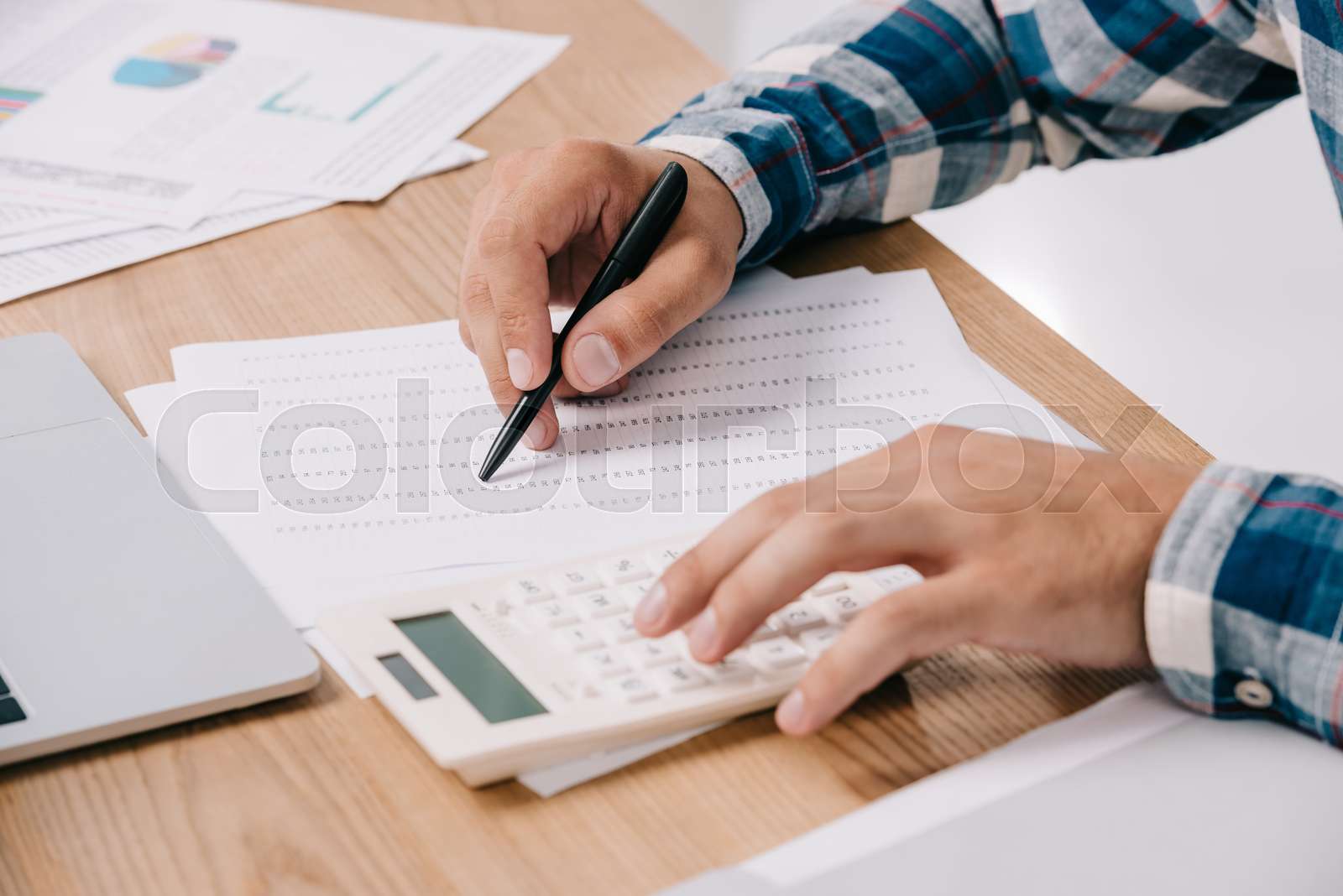 partial view of businessman making calculations at workplace with ...