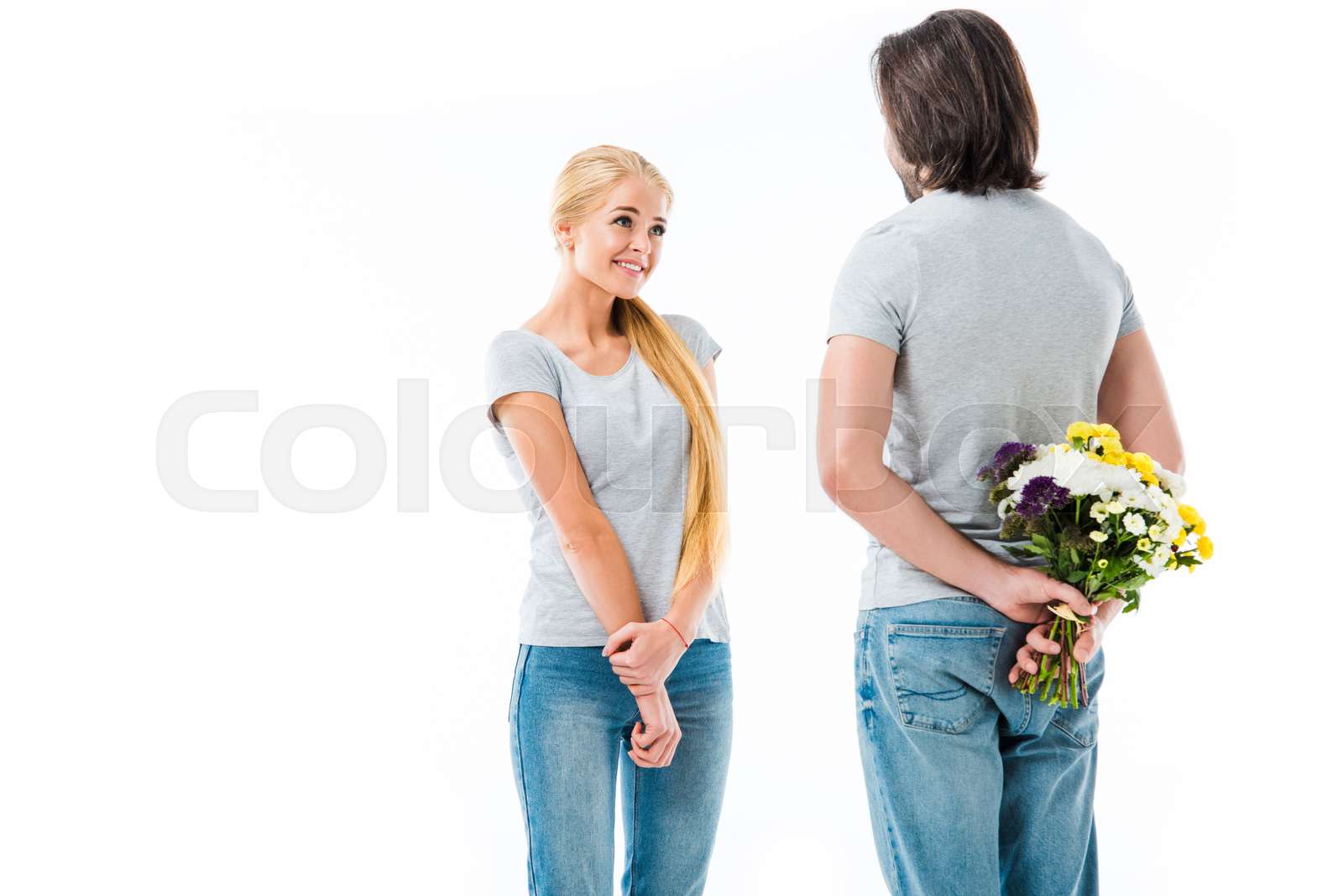 Lovely couple looking at each other, man holding flowers behind back ...
