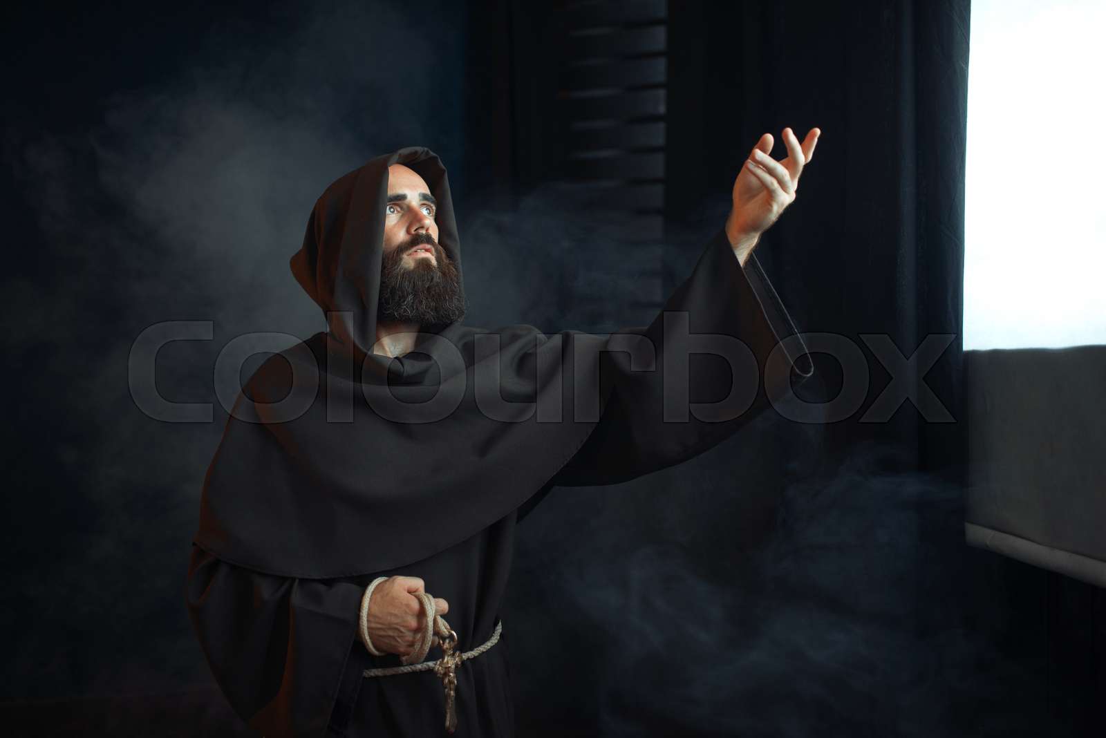 Medieval monk praying against a window with light | Stock image | Colourbox