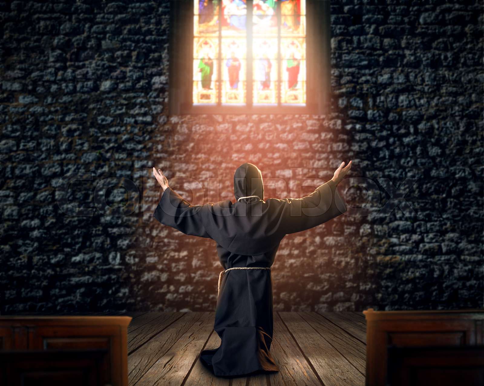 Medieval monk kneeling and praying in church | Stock image | Colourbox