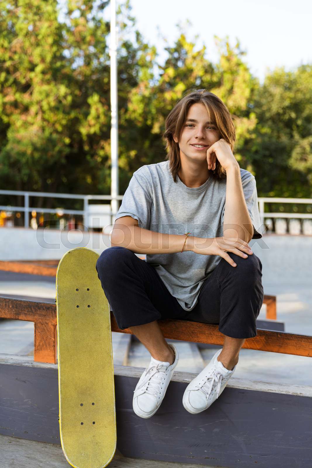 Handsome young skater guy sit in the park with skateboard. | Stock ...