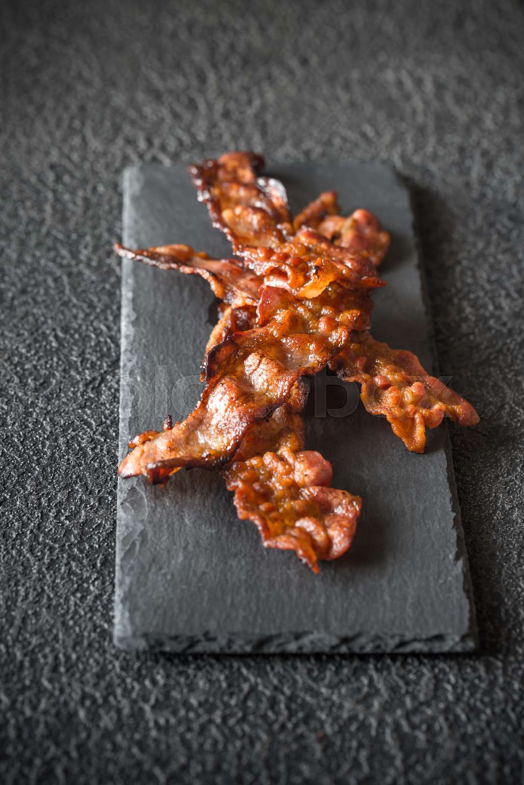 Fried bacon strips on the stone dark board | Stock image | Colourbox